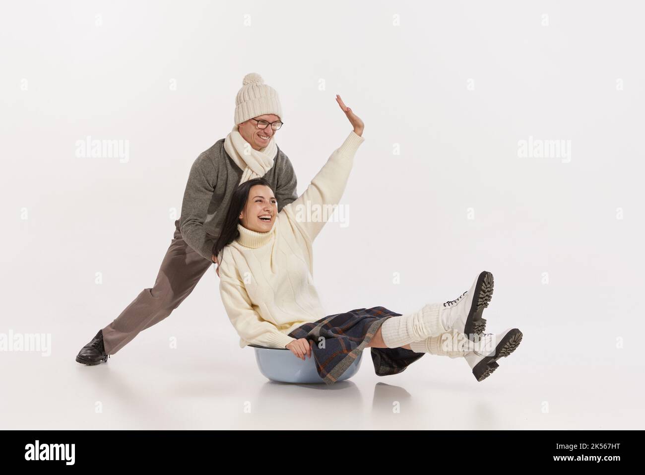 Portrait of cheerful young couple, man and woman having fun, sliding in ...