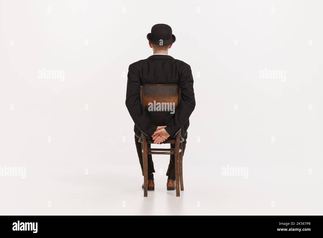 Portrait of stylish man in brown suit sitting on chair isolated over ...