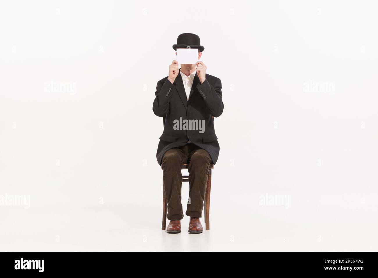 Portrait of stylish man in brown suit sitting on chair and covering ...
