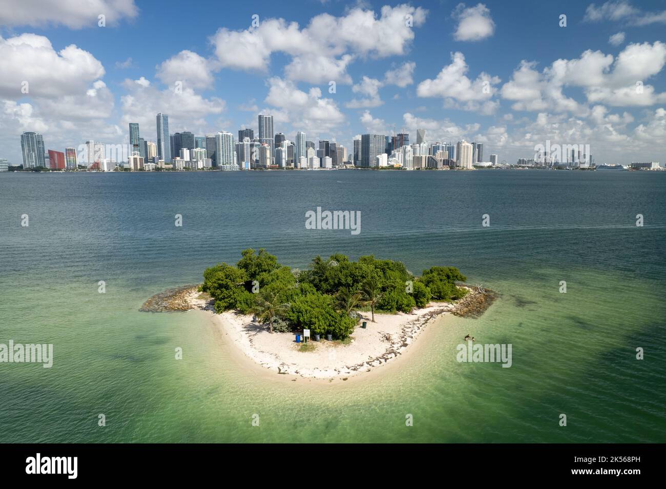 An aerial view of a small island covered in trees with the Miami city ...