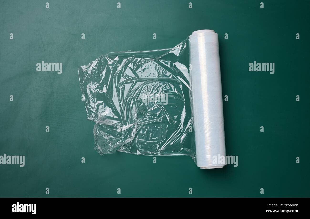 Roll of transparent food film for food packaging on a green background ...
