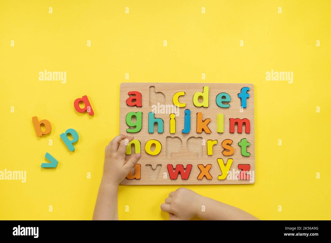 Childish hands holding alphabet wooden board with colored font letters ...