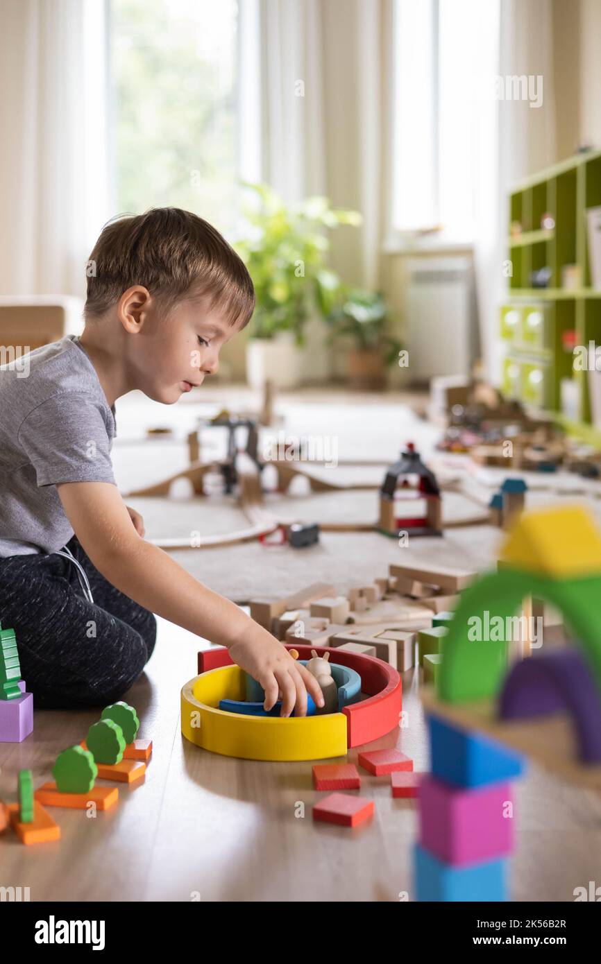 Confident male kid building fortress tower architecture wooden bricks ...