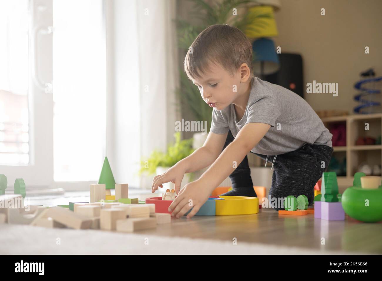 Confident male kid building fortress tower architecture wooden bricks ...