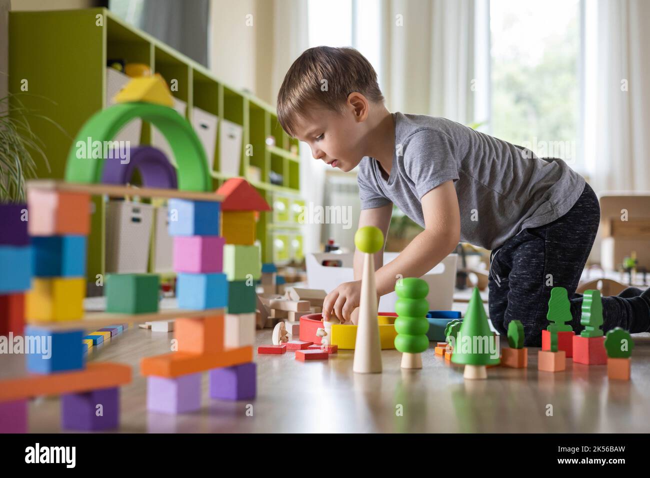 Confident male kid building fortress tower architecture wooden bricks ...