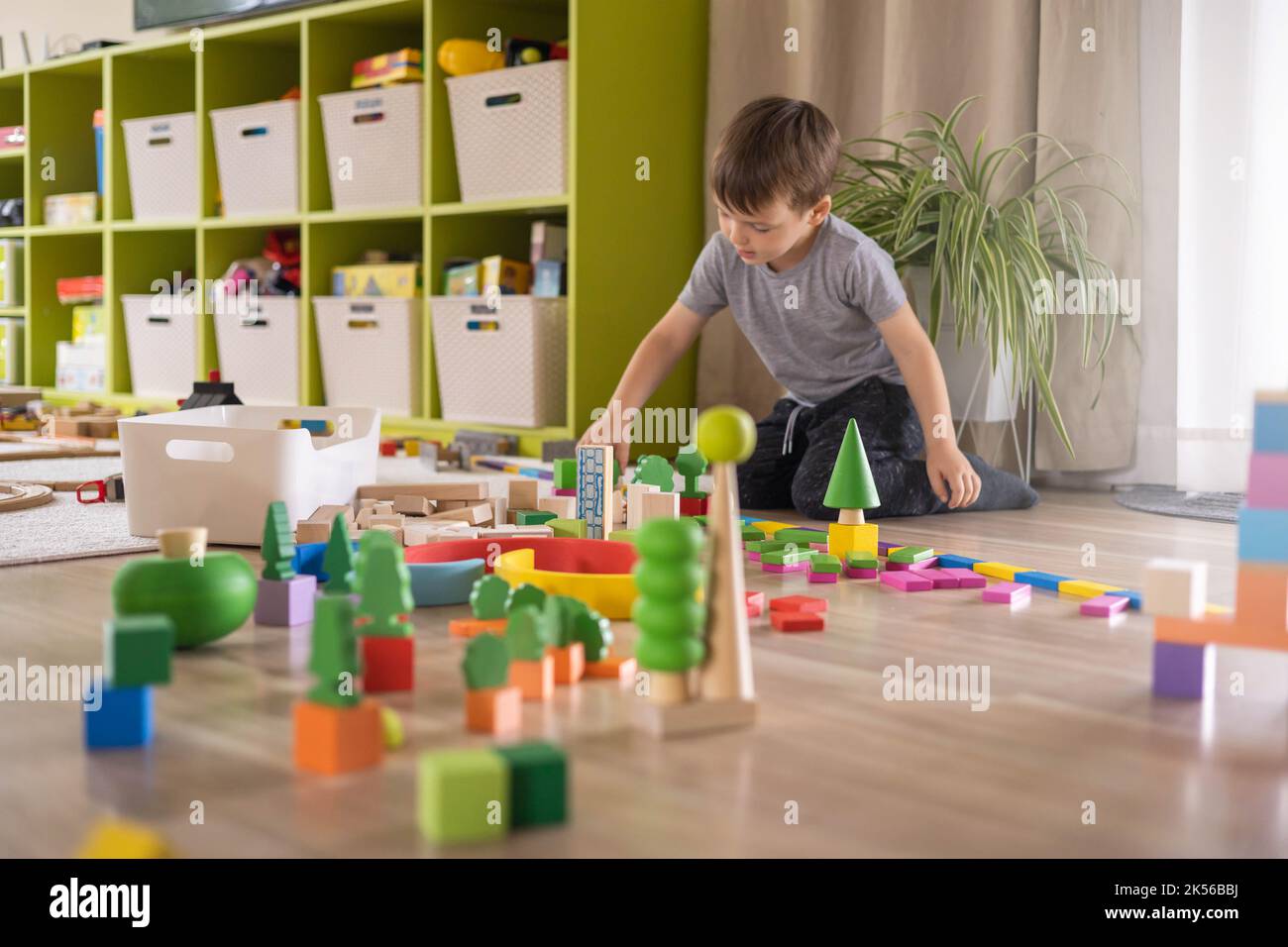 Confident male kid building fortress tower architecture wooden bricks ...