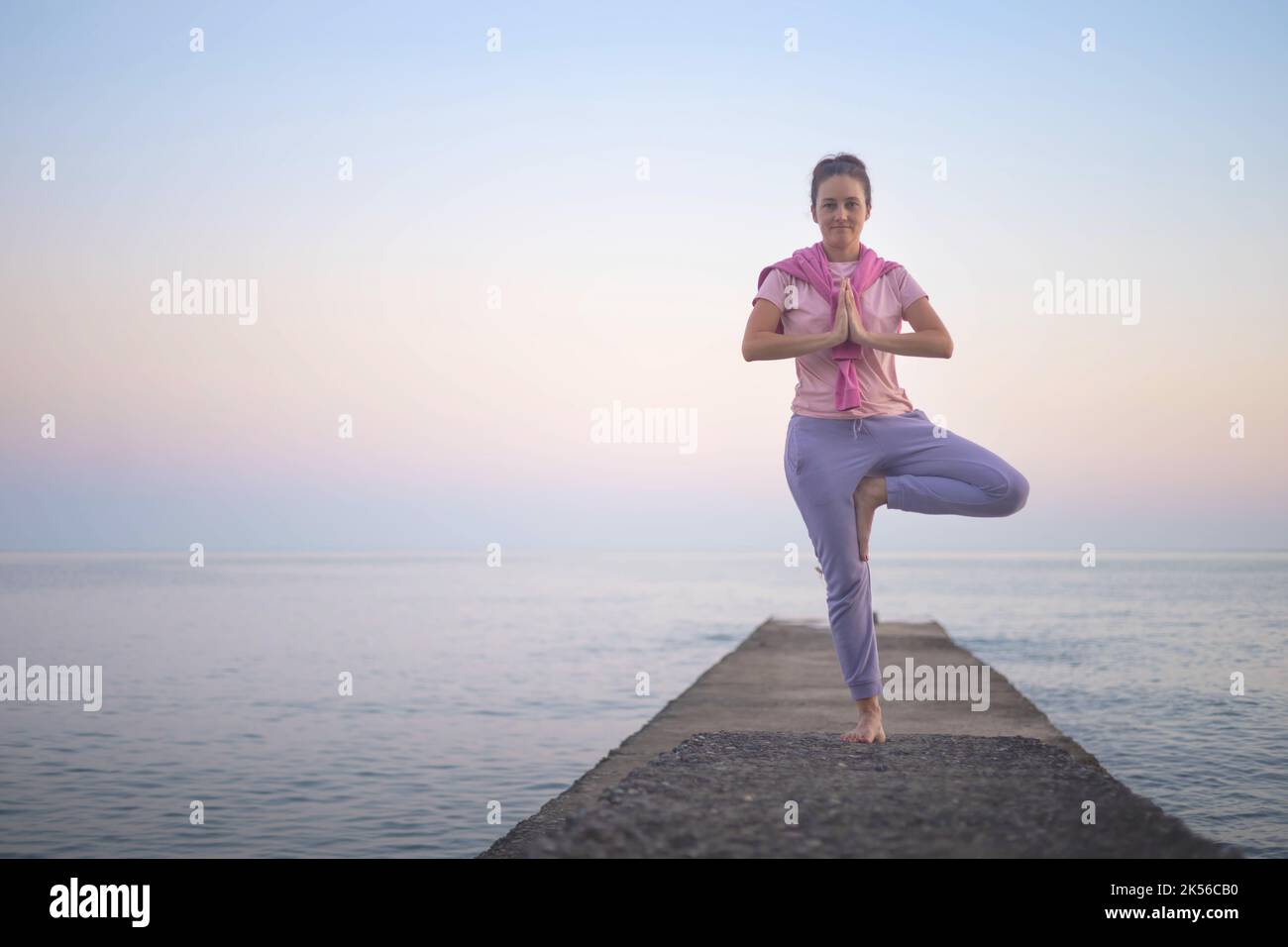 Active female practicing yoga vrikshasana tree pose hands namaste at ...