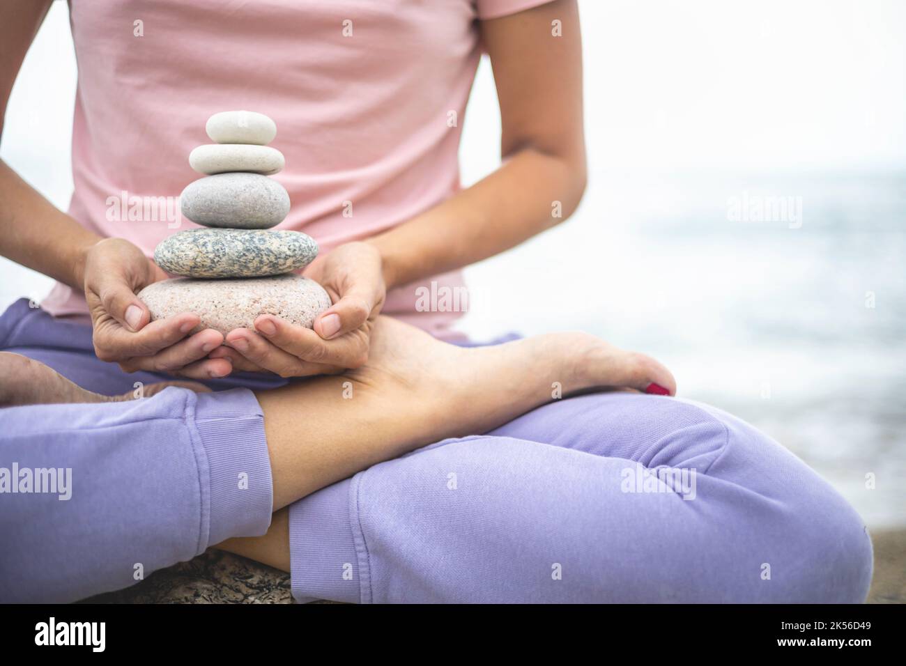 Yoga woman hands holding pebble tower sitting lotus position meditation ...