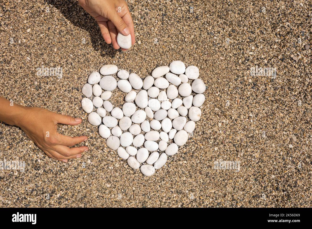 Female hands arrangement white smooth pebble romantic heart shape love ...
