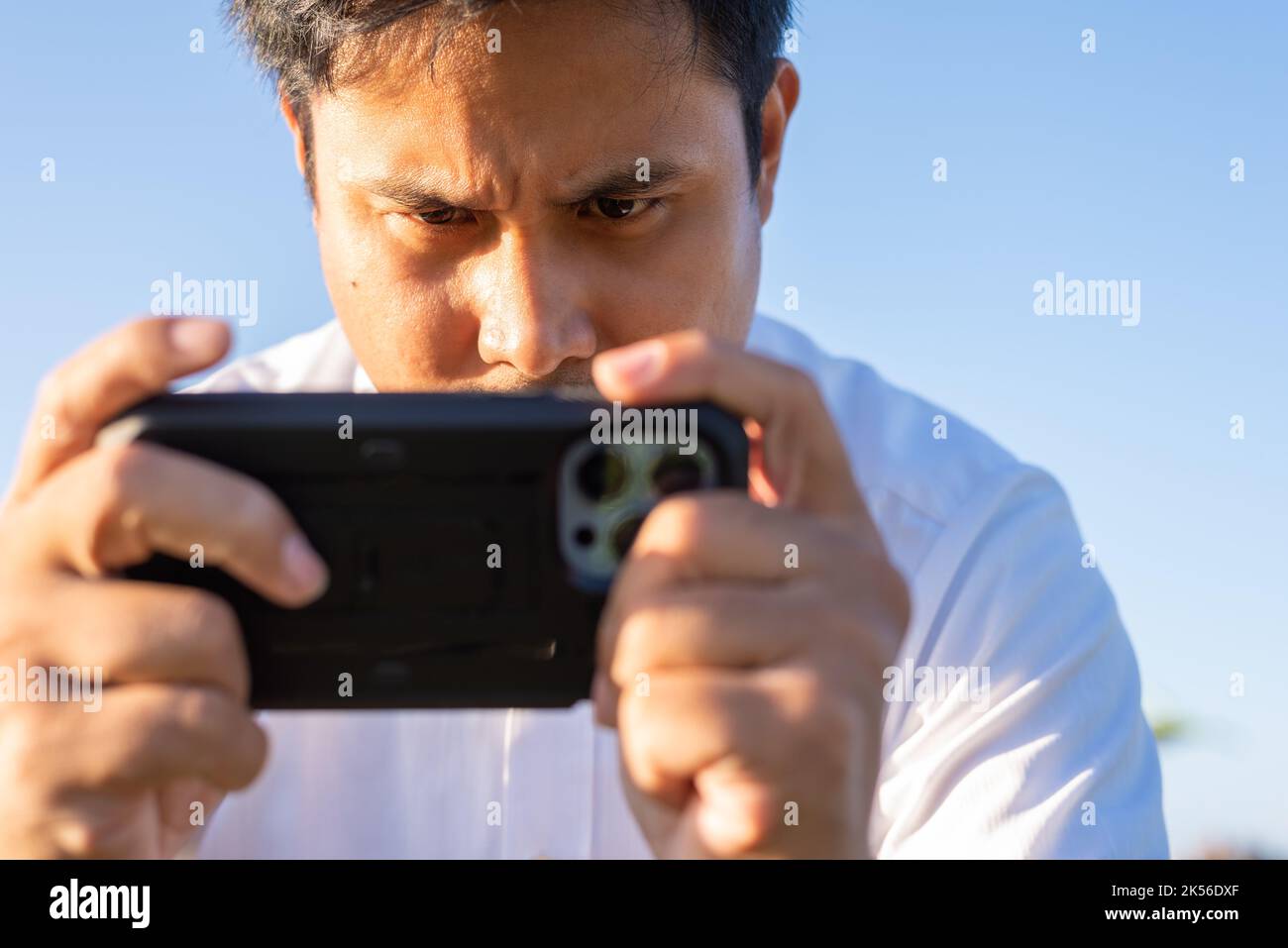 An Asian Filipino man is focusing on playing mobile games on his ...