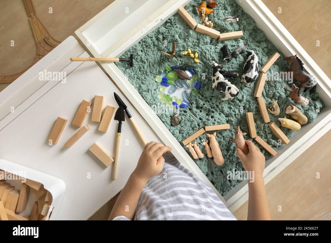 Cute baby boy playing sensory box kinetic sand table with farm animals ...