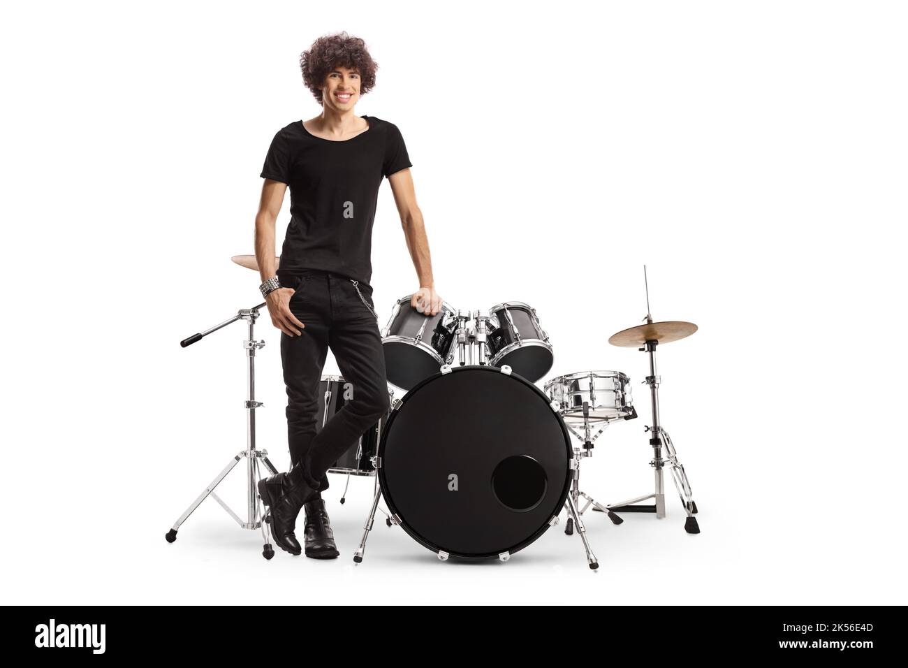 Young male drummer standing next to a drum kit isolated on white ...