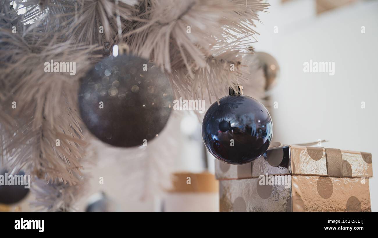 Silver polka dot giftbox placed under a white christmas holiday tree ...