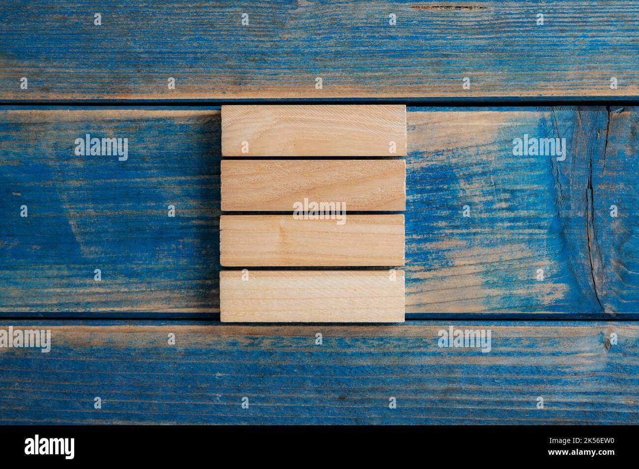 Stack of four blank wooden blocks or pegs placed over aged blue ...