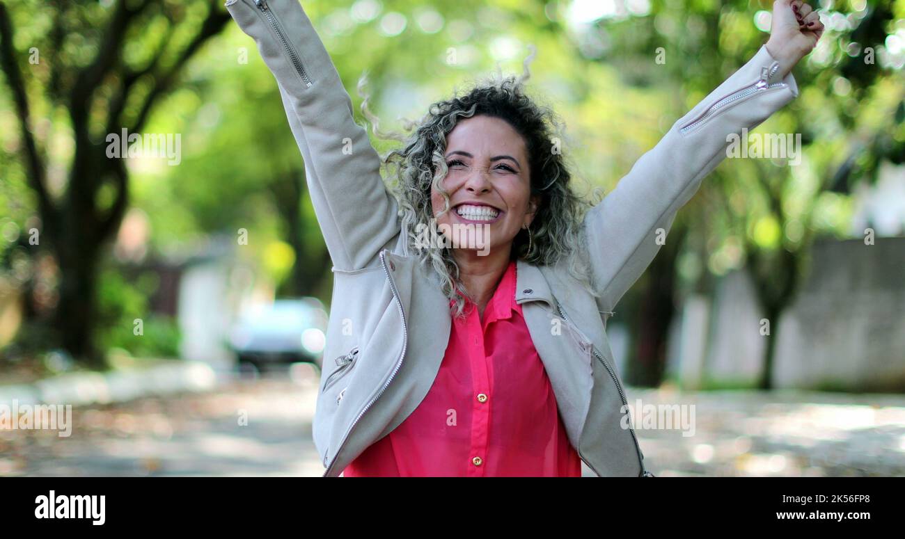 Ecstatic woman jumping with joy celebrating success outside in street ...