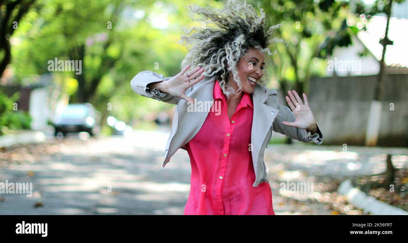 Ecstatic woman jumping with joy celebrating success outside in street ...