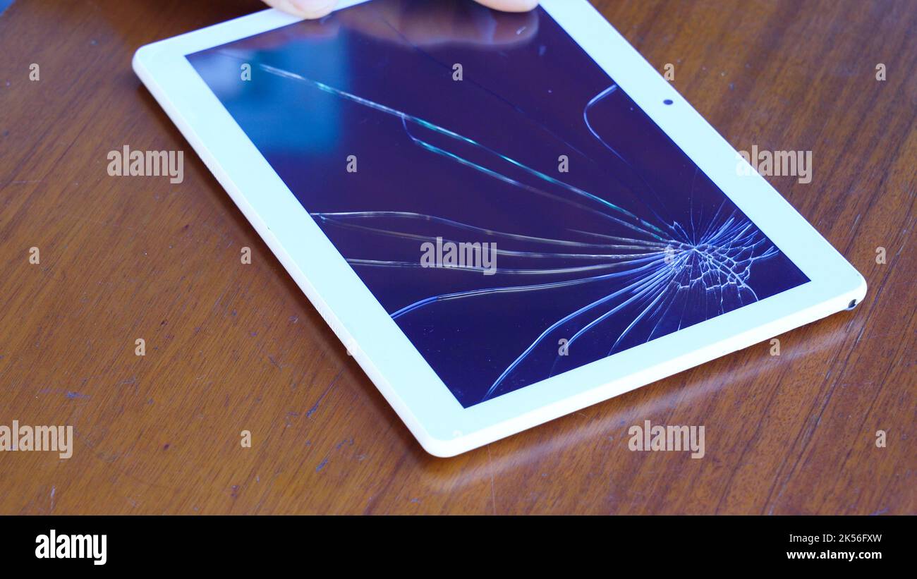 Tablet computer with a broken glass screen lying on the table Stock ...