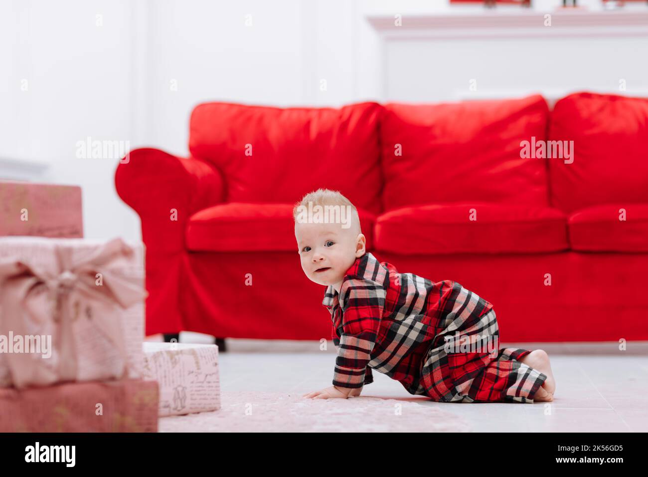 Adorable caucasian baby boy is crawling by the Christmas tree, many ...