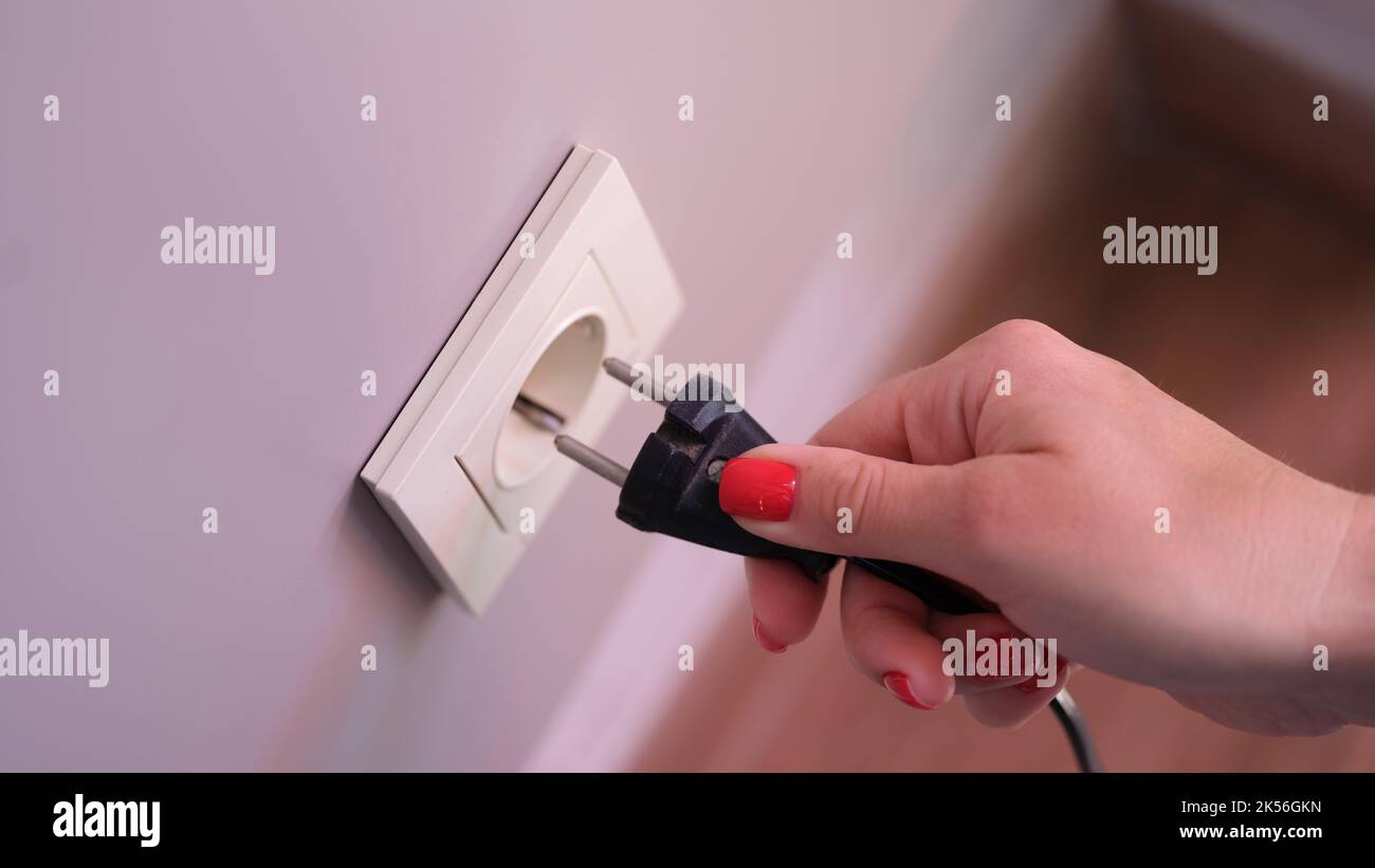 Hand inserts plug into socket closeup. Use of promising energy in home ...