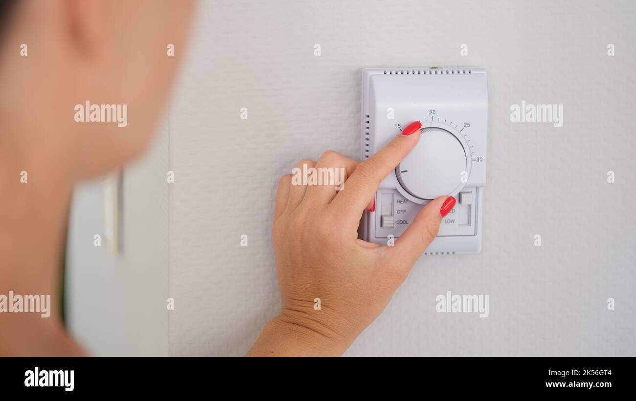 Hand adjusts button of the control unit of heating and cooling system ...