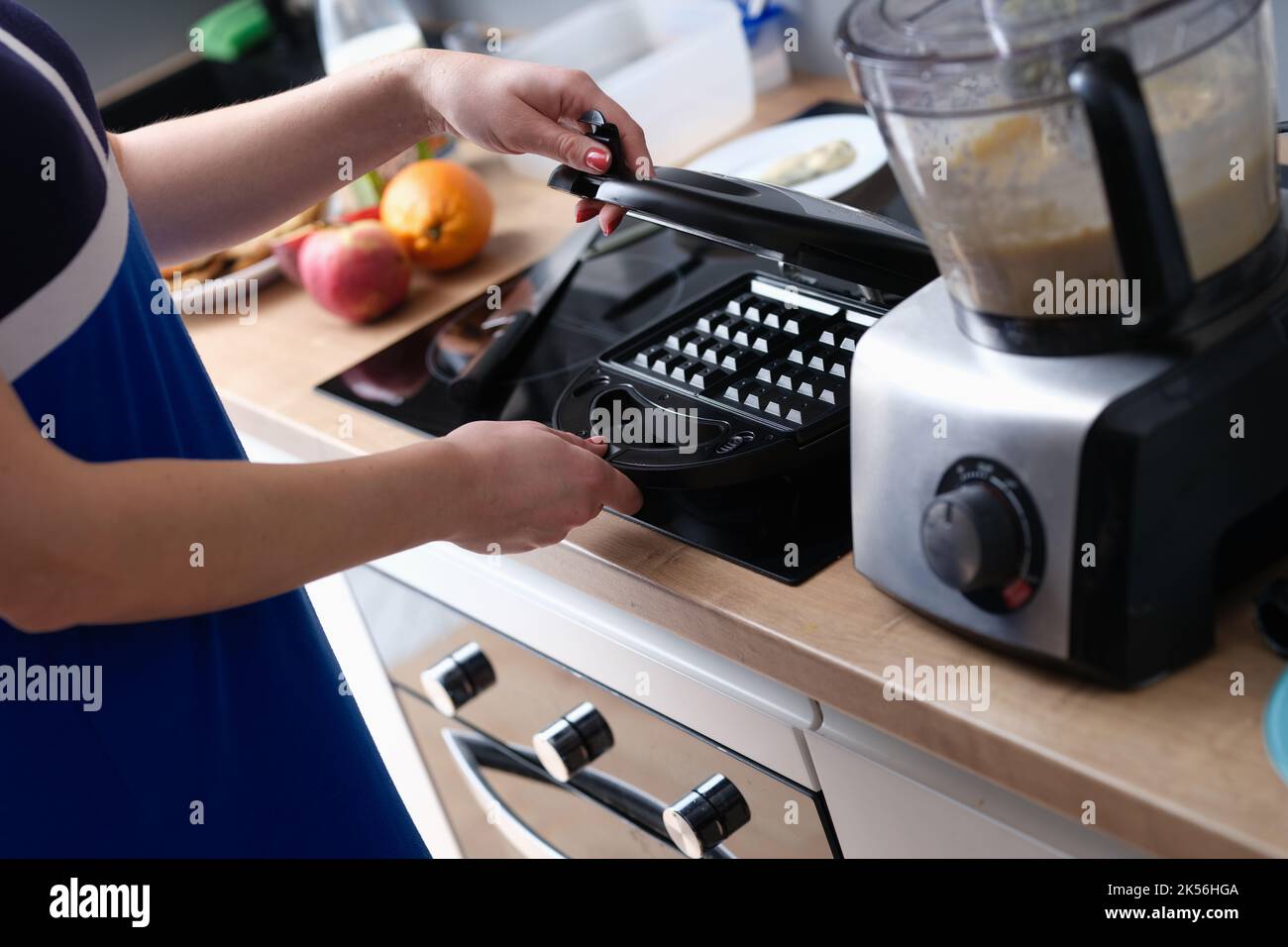 Woman opens Belgian waffle iron to make waffles in kitchen Stock Photo ...