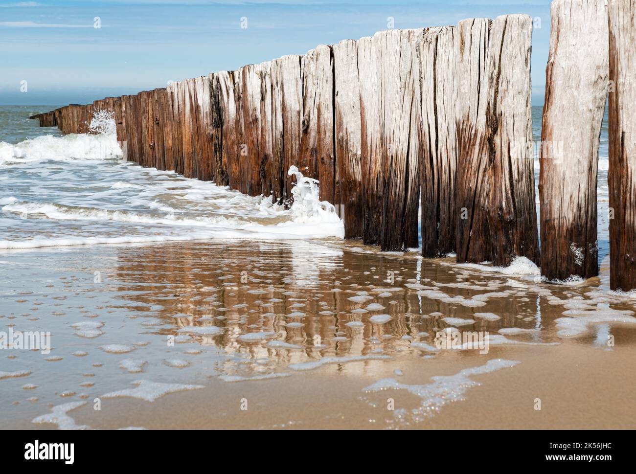 Sand, a wooden pier and reflections at the Cadzand beach, The ...