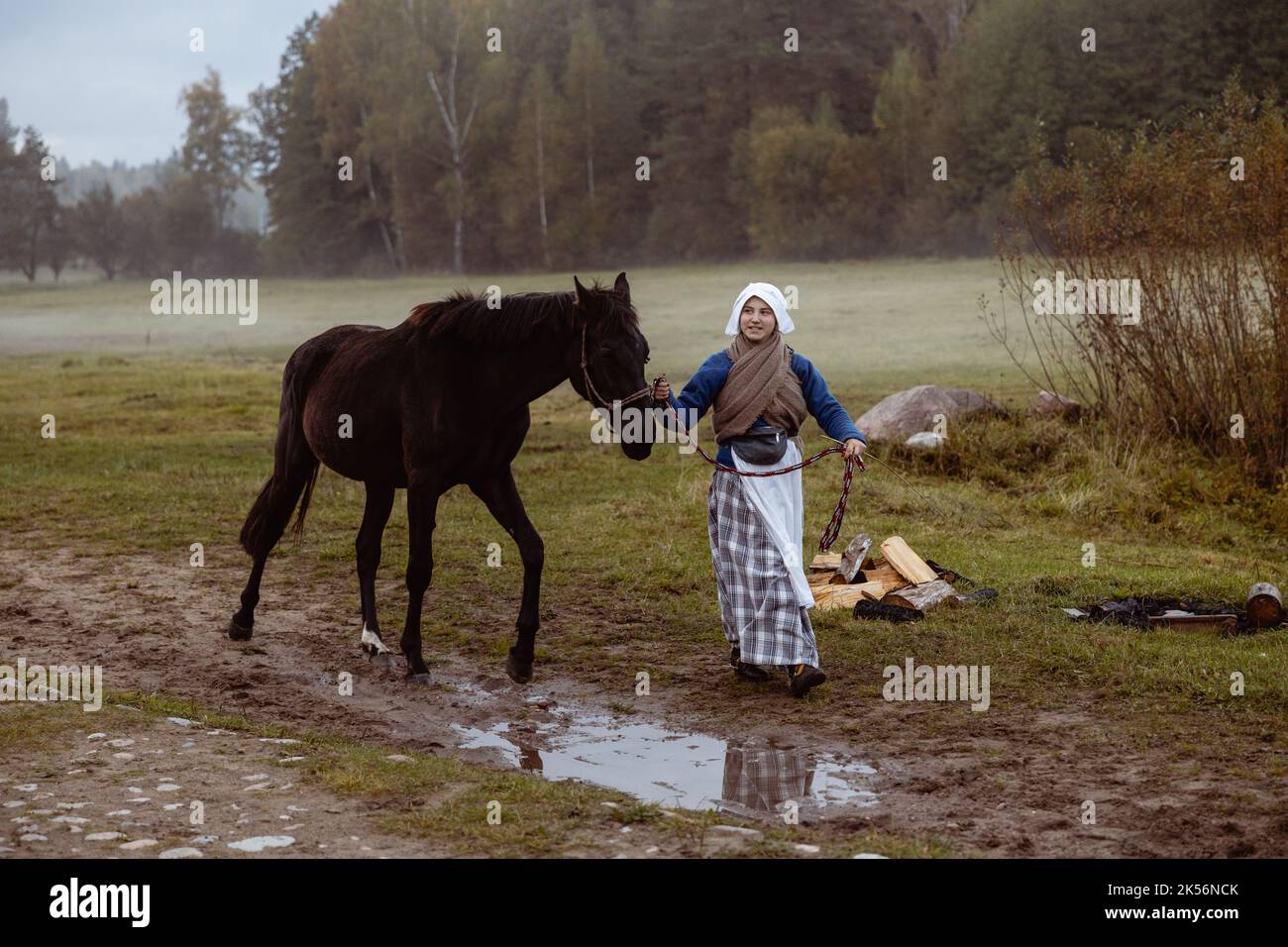 A young woman dressed as a 17th century European peasant woman leads a ...