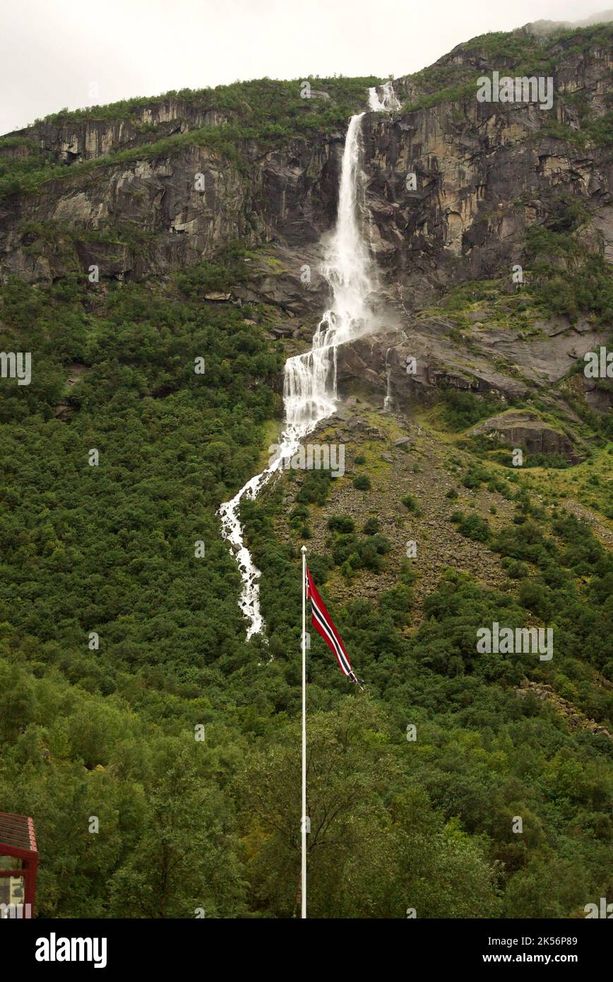 Norwegian flag (pennon) blowing in the wind, with a waterfall in the ...