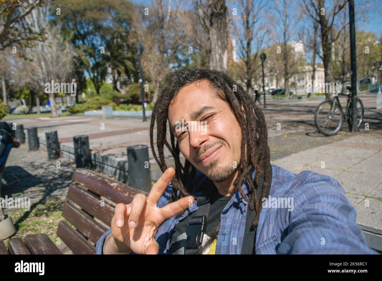 young latin venezuelan man with dreadlocks is sitting in a square ...
