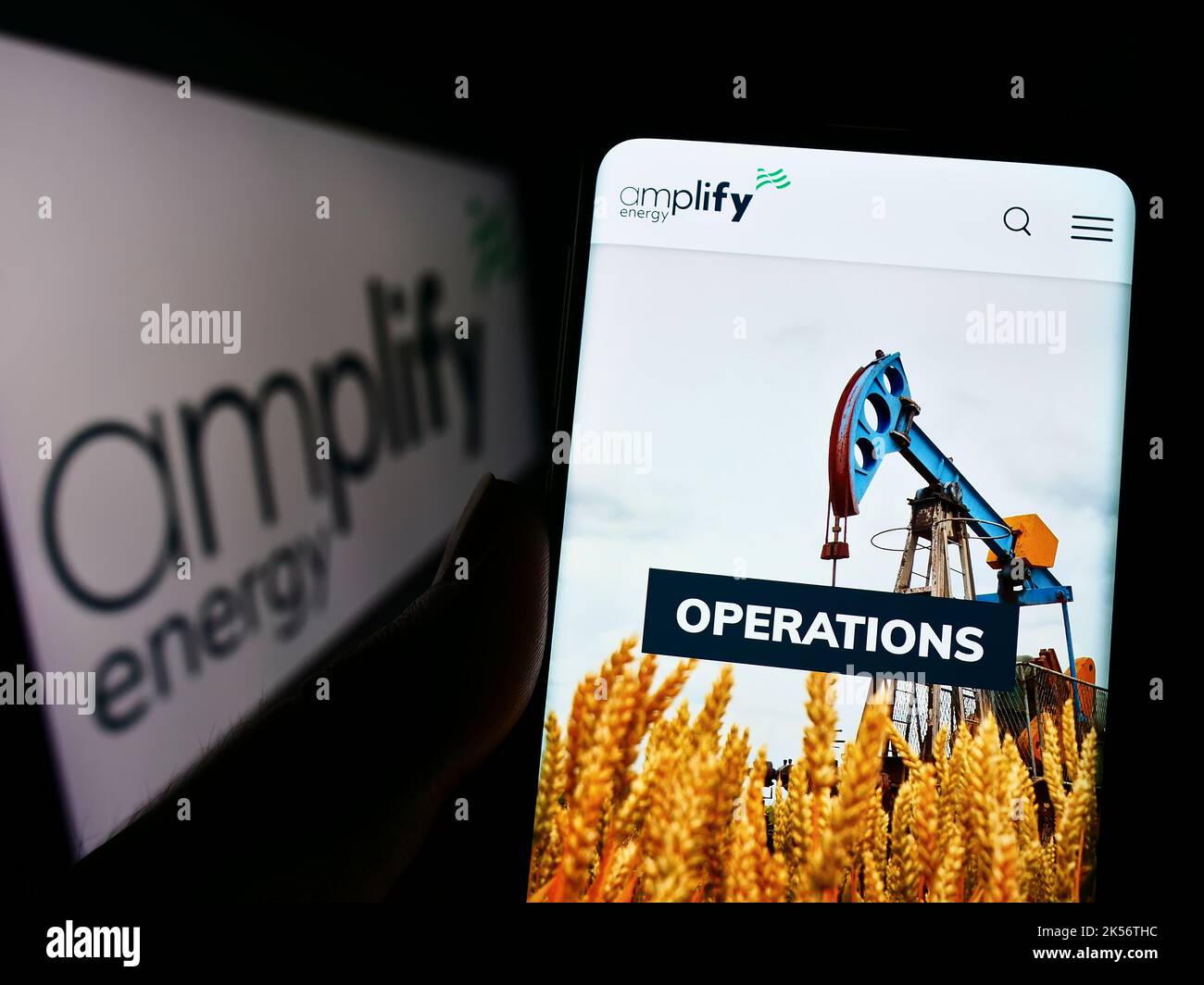 Person holding cellphone with webpage of US petroleum company Amplify Energy Corp. on screen in ...