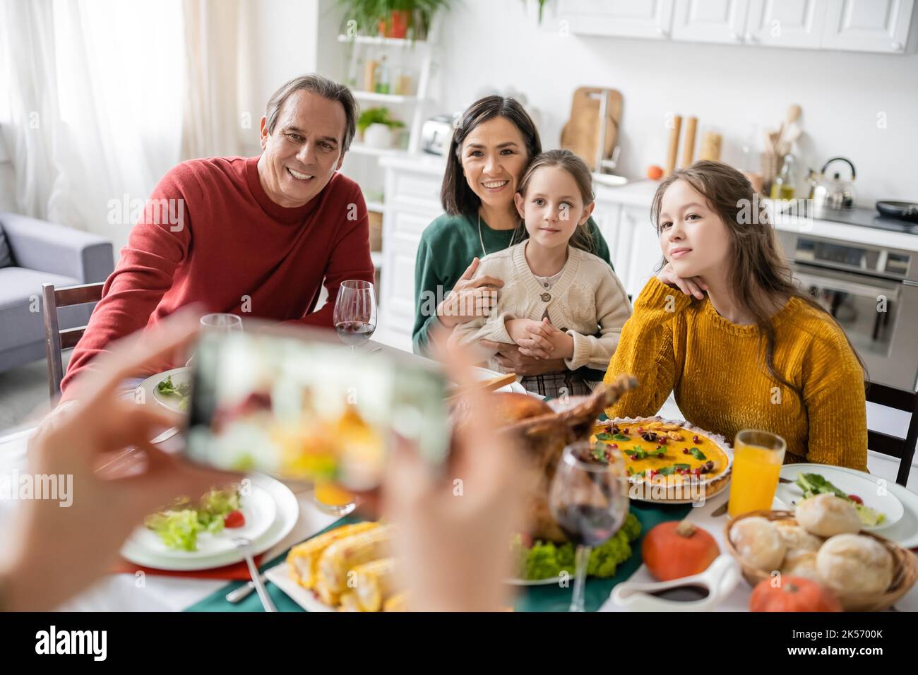 Interracial family smiling near delicious thanksgiving dinner and woman ...