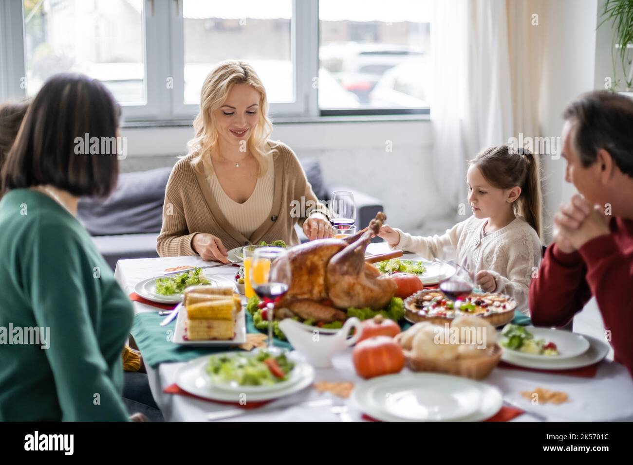 Positive woman sitting near parents and children during thanksgiving ...