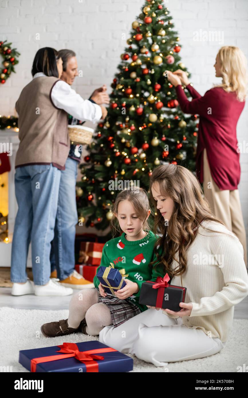 blurred multicultural family decorating christmas tree near girls ...
