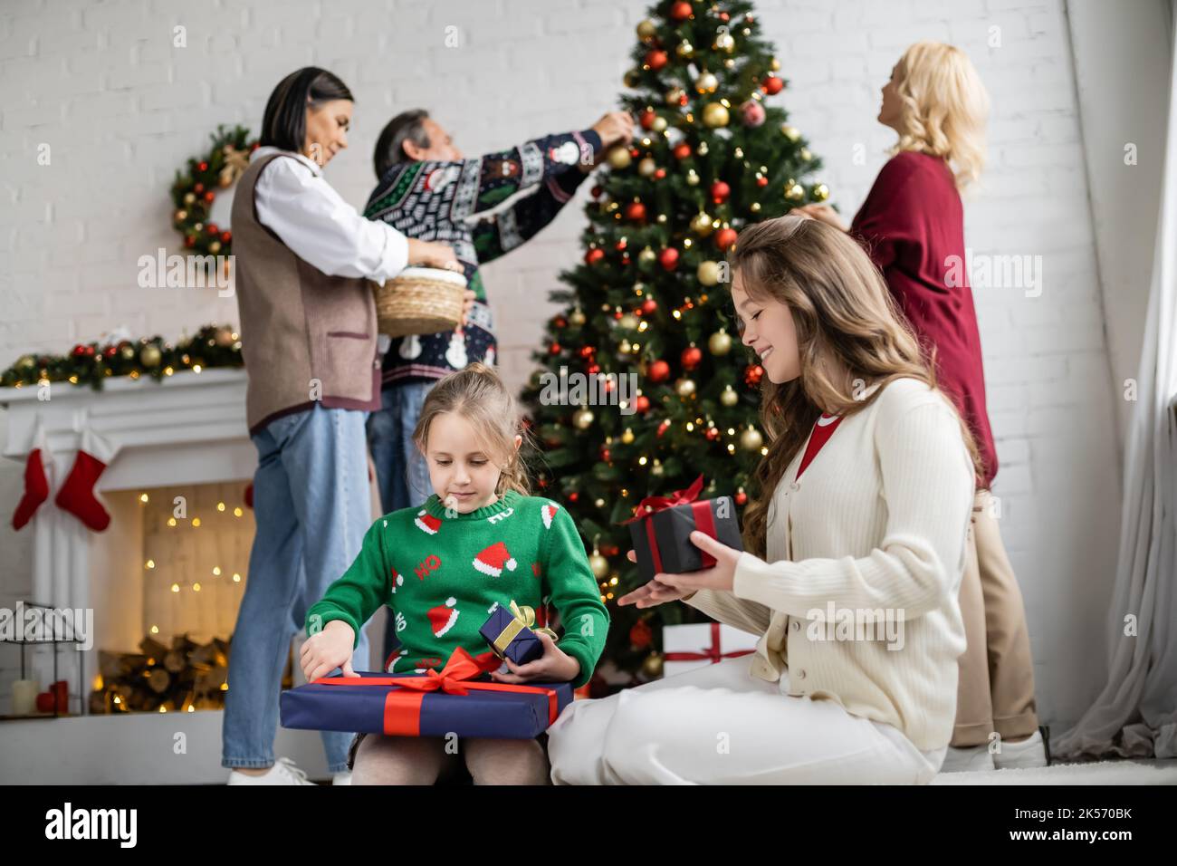 girls looking at new year presents while interracial family decorating ...
