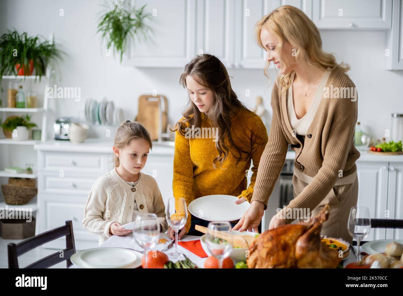 smiling blonde woman serving table for thanksgiving dinner with ...