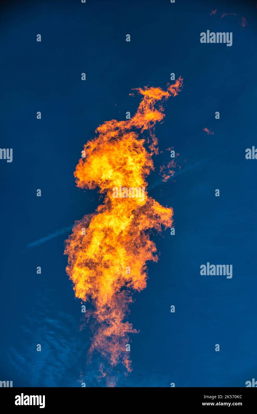 Vibrant orange flame against a deep blue sky. Abstract image of burning ...