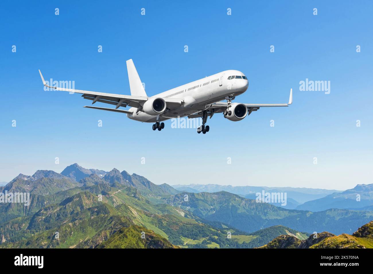 Airplane is flying over low clouds and mountains with autumn forest ...