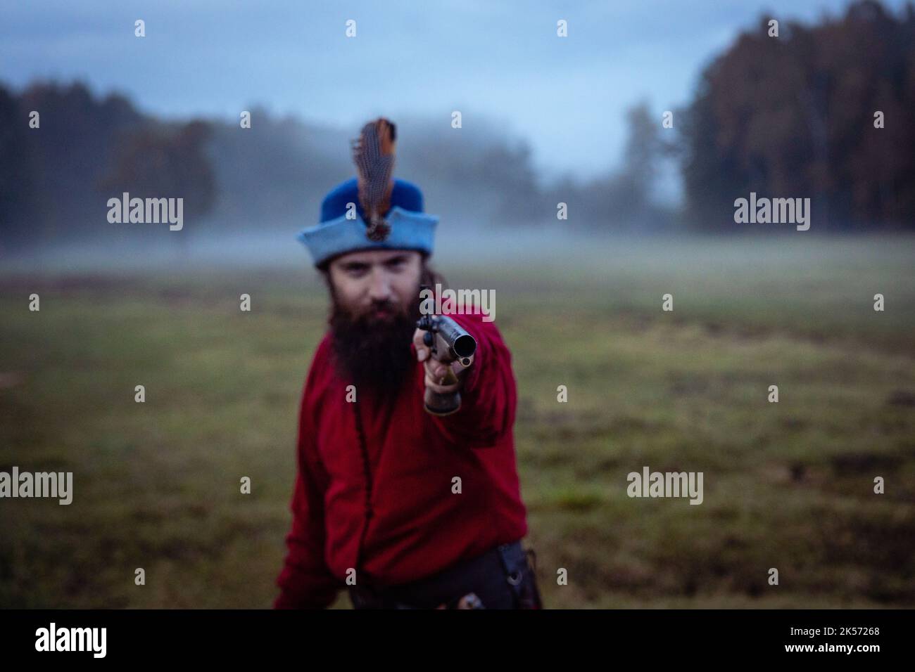 A man in a red caftan and hat of the 17th century with a dueling pistol ...