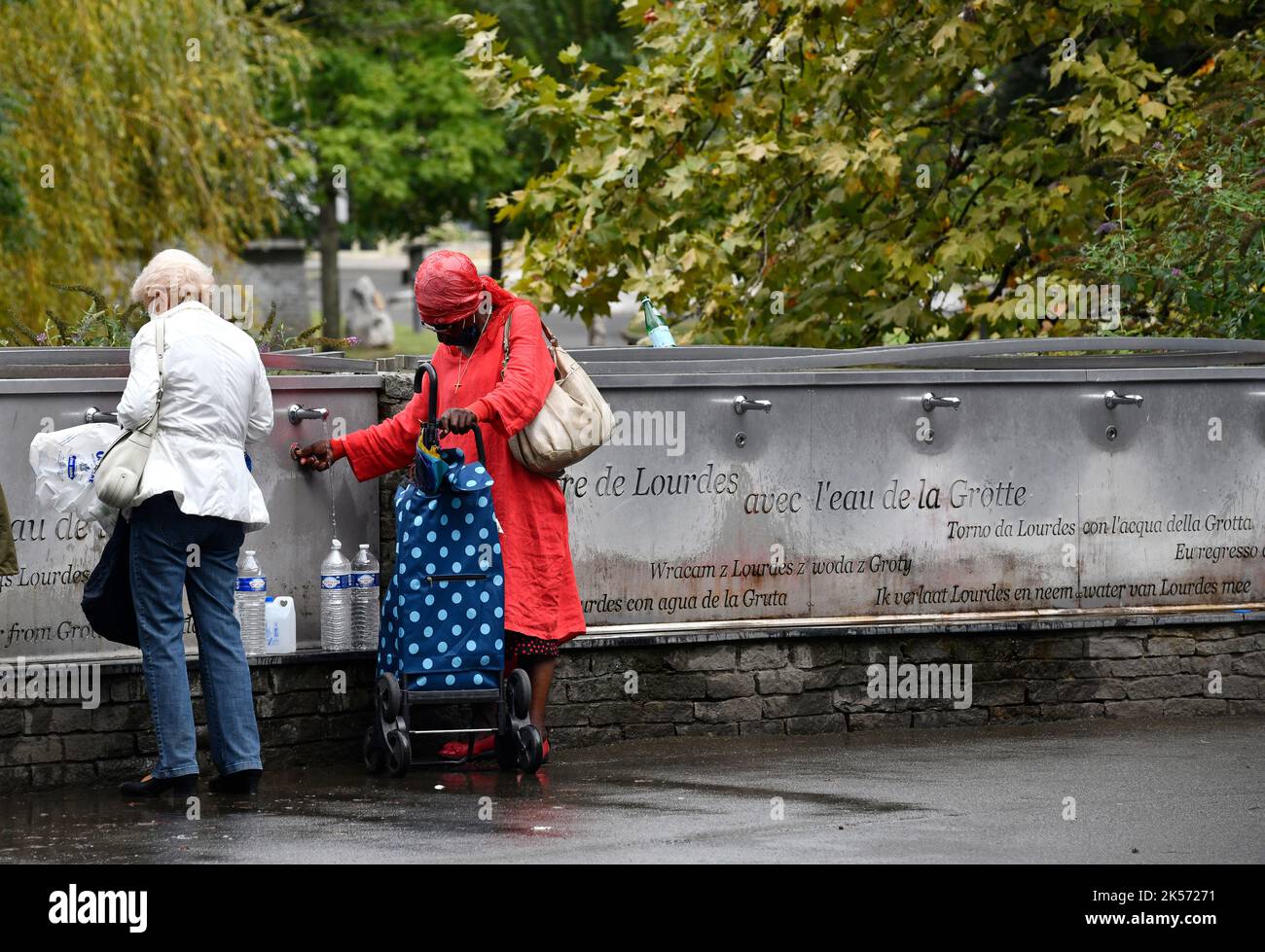 Lourdes, Hautes-Pyrénées, France. Christian pilgrims collecting Lourdes ...