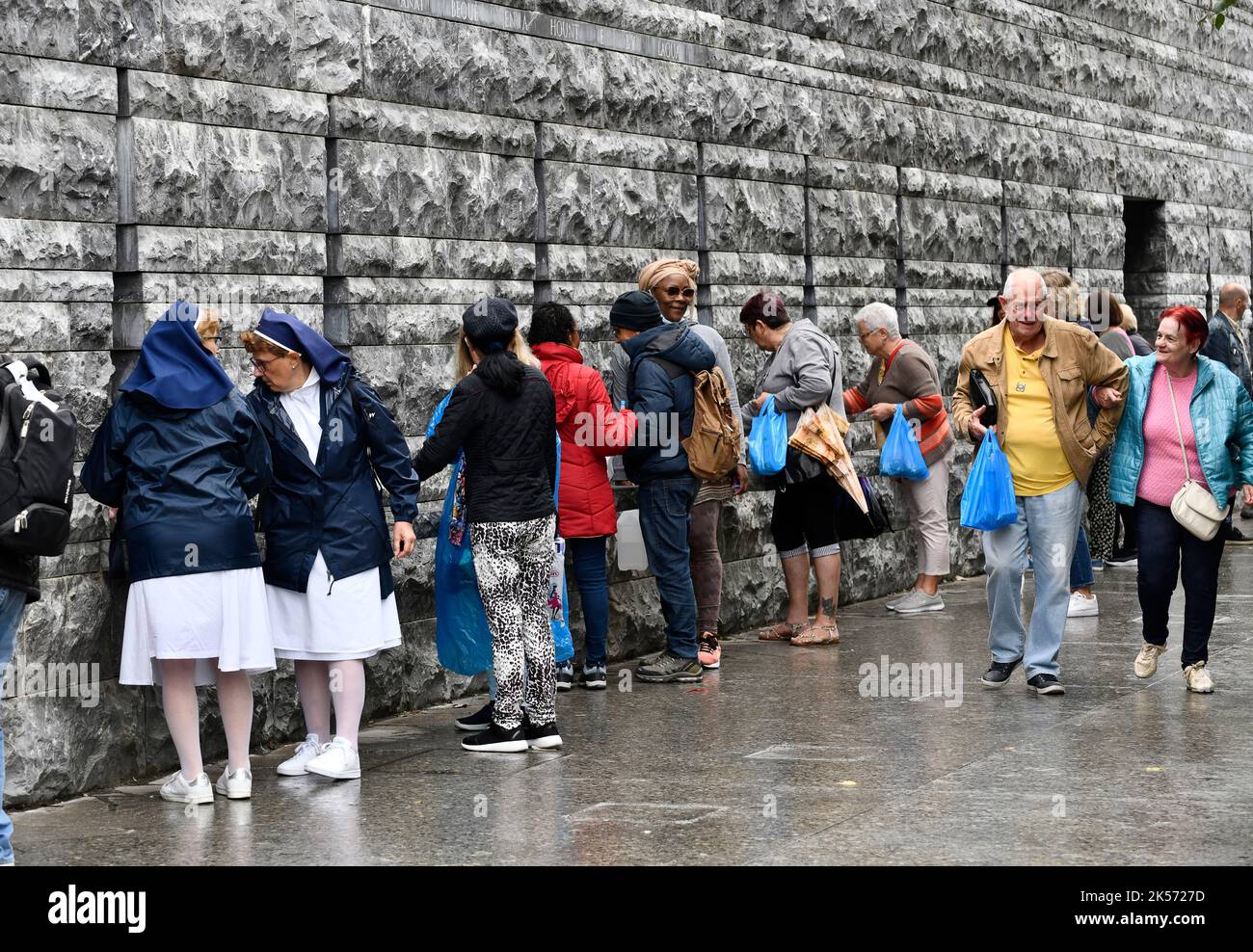 Lourdes, Hautes-Pyrénées, France. Christian pilgrims collecting Lourdes ...