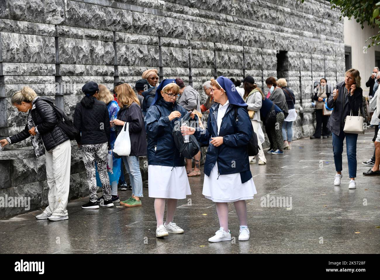 Lourdes, Hautes-Pyrénées, France. Christian pilgrims collecting Lourdes ...