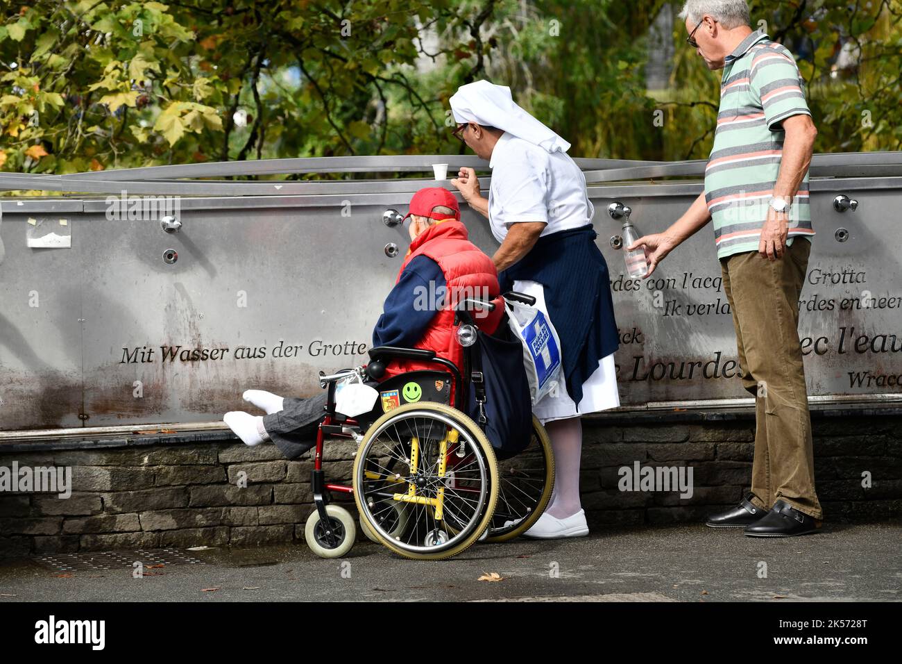 Lourdes, Hautes-Pyrénées, France. Christian pilgrims collecting Lourdes ...