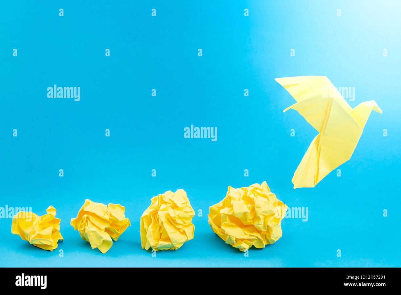 Yellow crumpled paper balls and a origami dove on blue background Stock ...