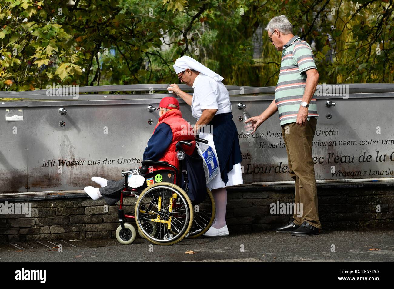 Lourdes, Hautes-Pyrénées, France. Christian pilgrims collecting Lourdes ...
