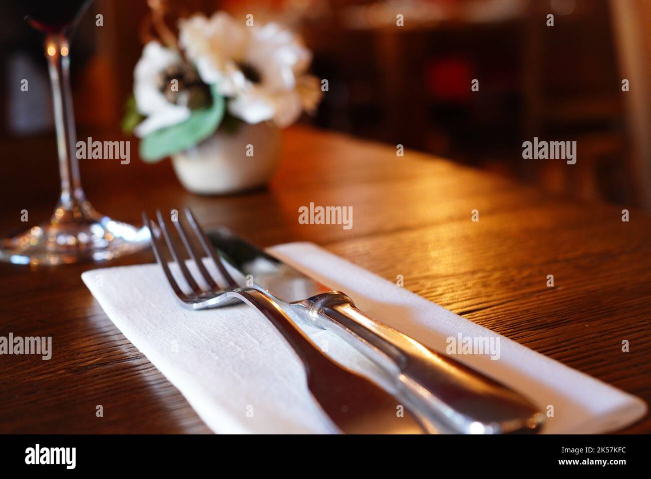 Fork and knife cutlery and napkins at a table in a moody restaurant ...