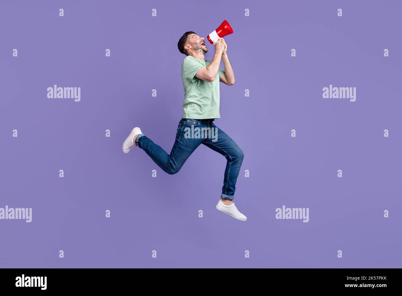 Full length photo of nice young guy screaming jumping megaphone ...