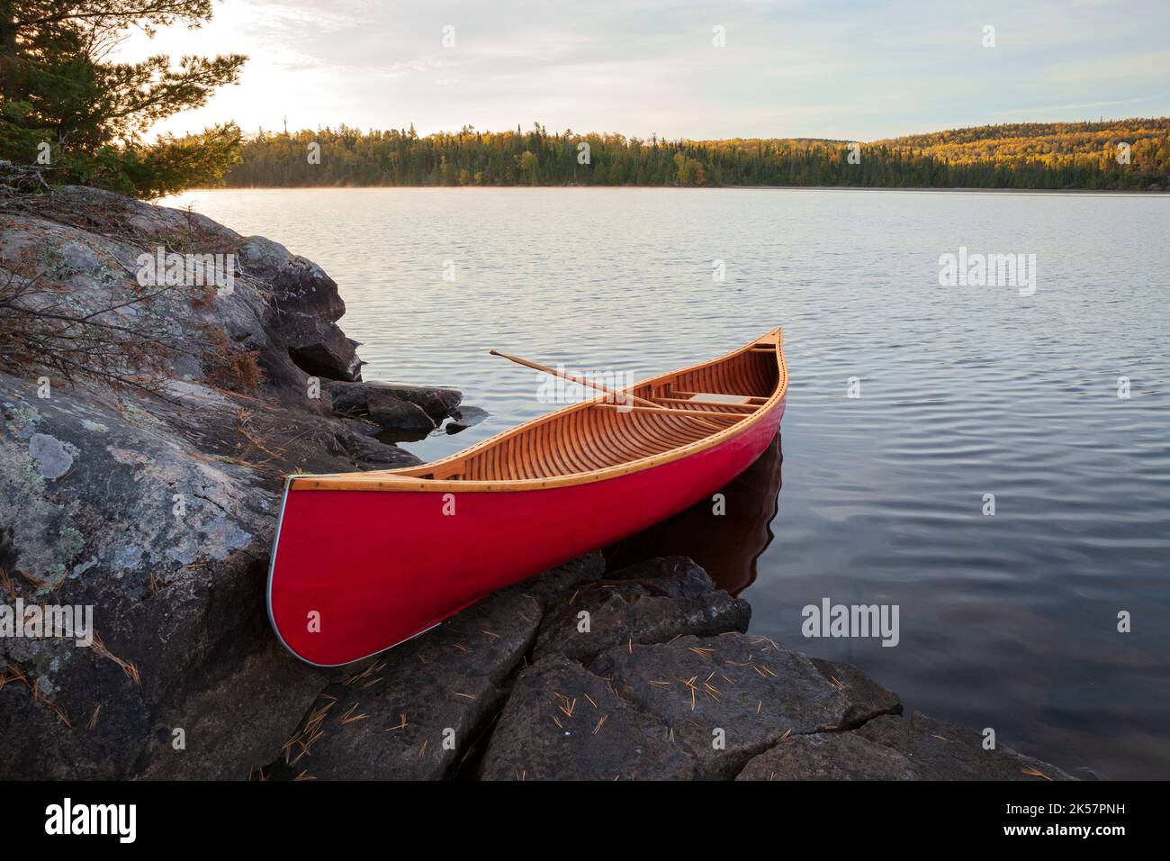 Red wood canoe on rocky island in the Boundary Waters on a bright fall ...