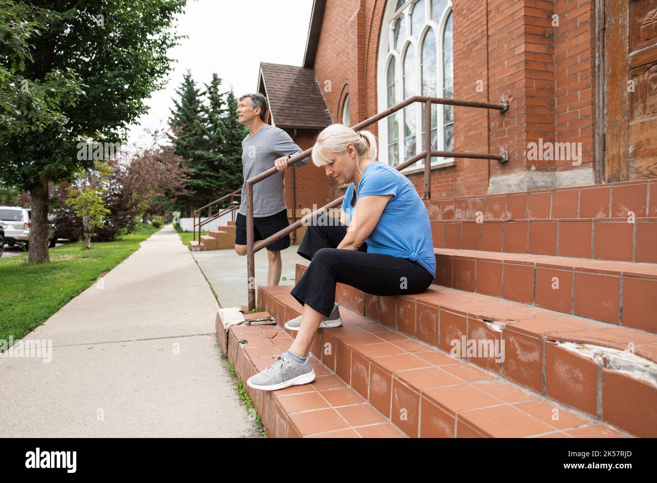 Couple tying running shoes and stretching on church steps Stock Photo ...