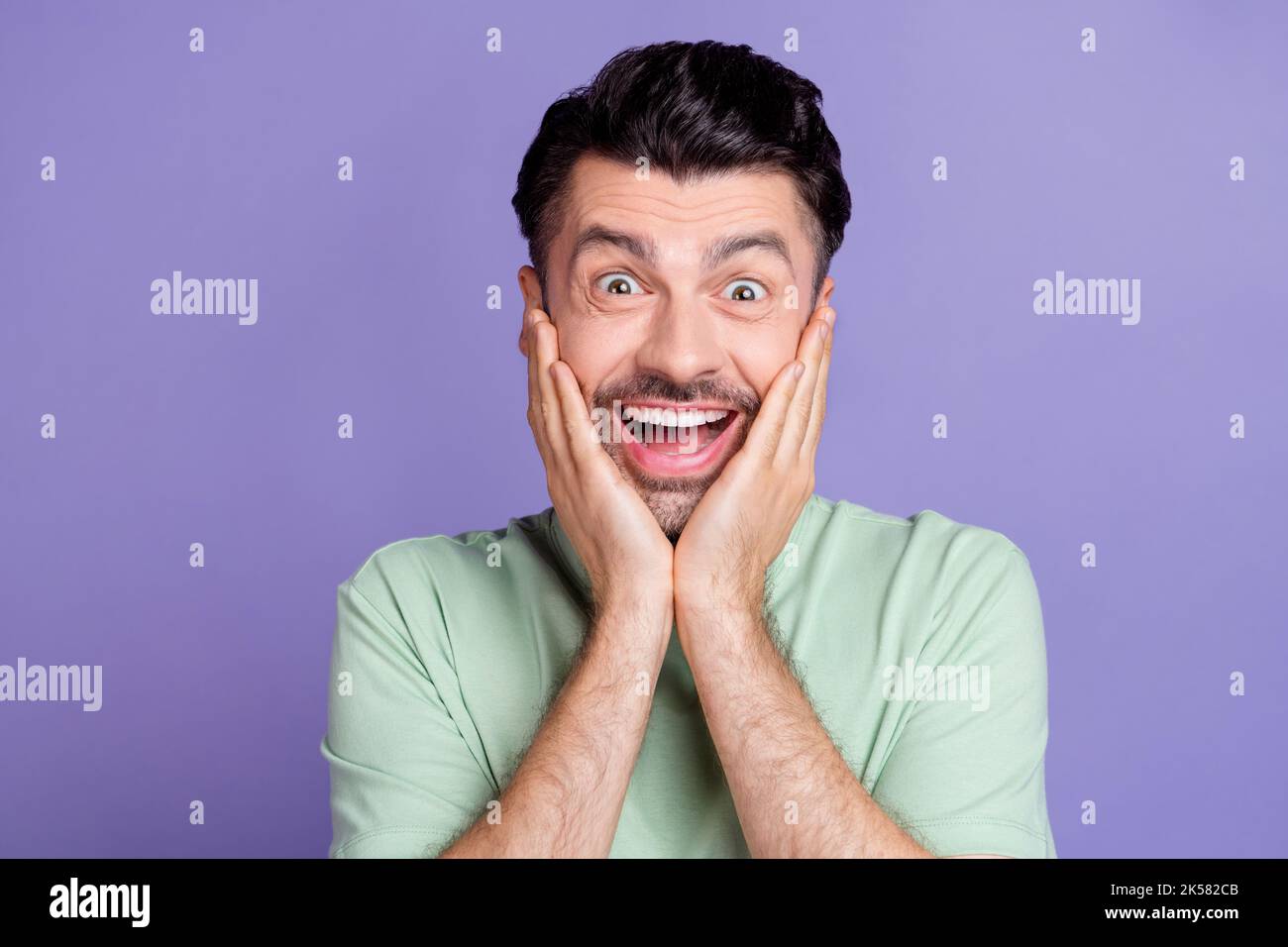 Portrait of crazy impressed positive man with brunet hairdo dressed t ...