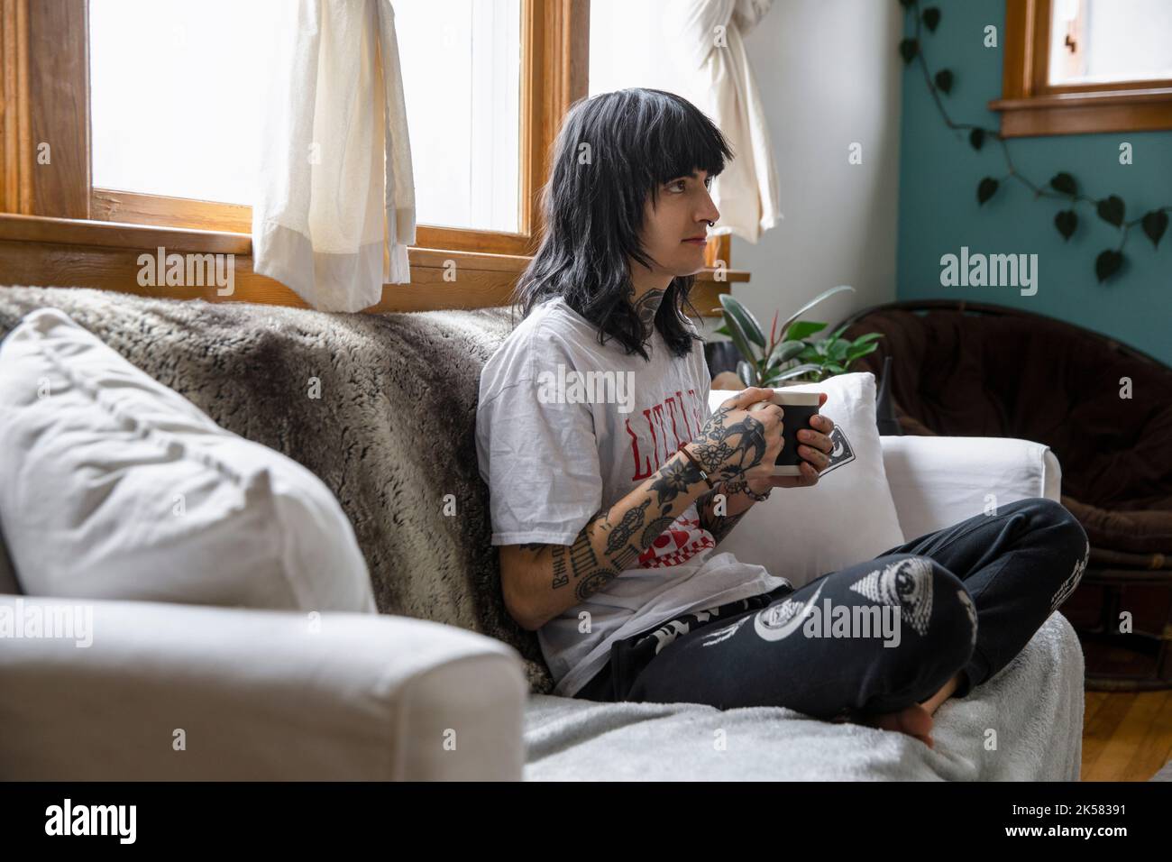 Young transgender woman relaxing with coffee on sofa Stock Photo - Alamy